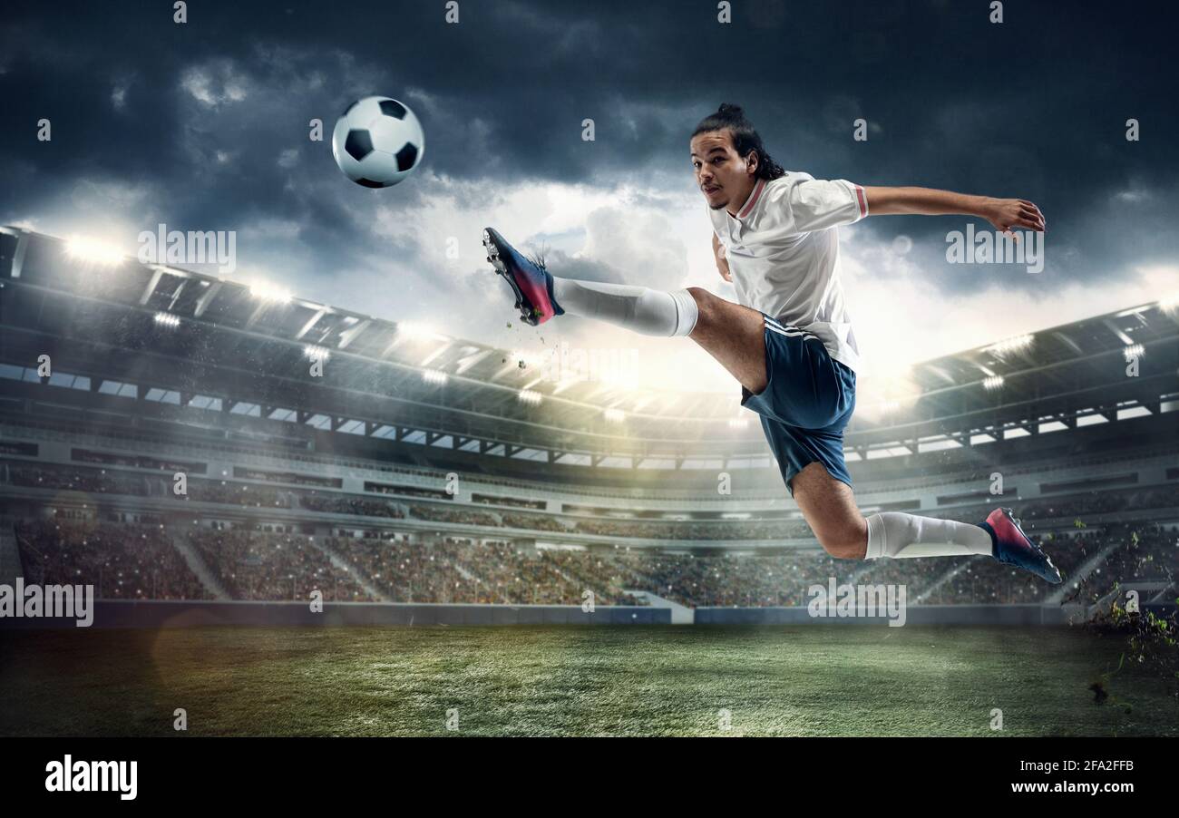 Male soccer, football player catching ball in jump at the stadium ...