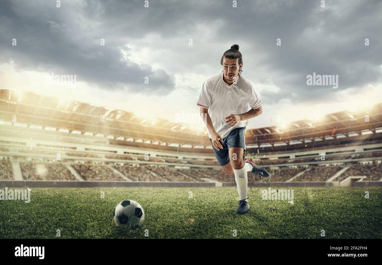 Male soccer, football player catching ball in jump at the stadium ...