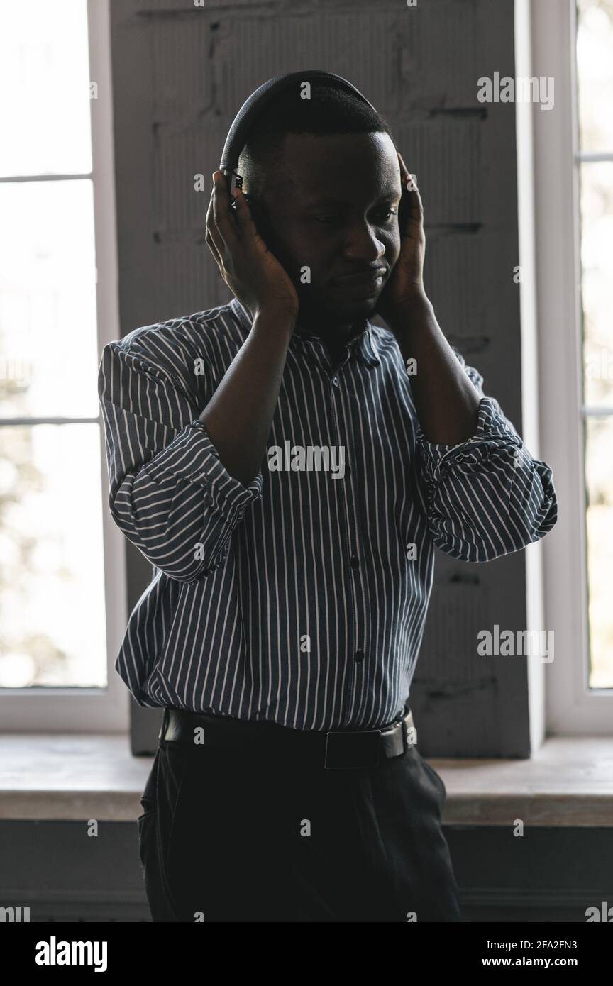 black guy on a gray background listens to music enjoys great sound ...