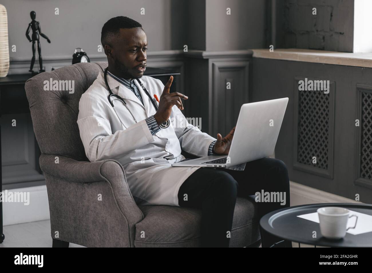 dark-skinned doctor talking on skype zoom with laptop waving Stock ...