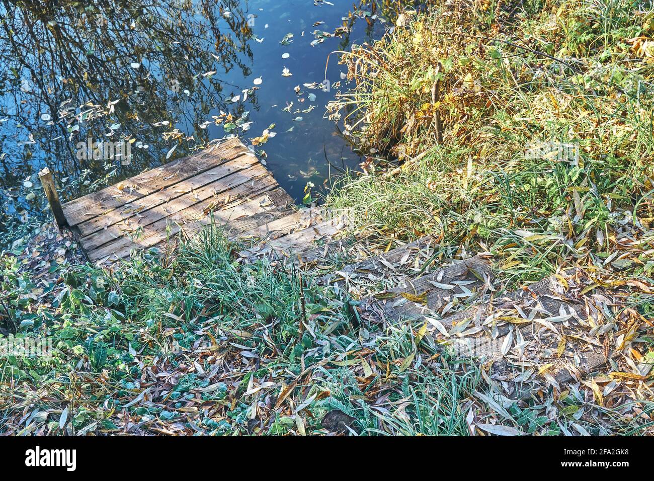Rustic wooden steps to calm narrow river with green grass covered with ...