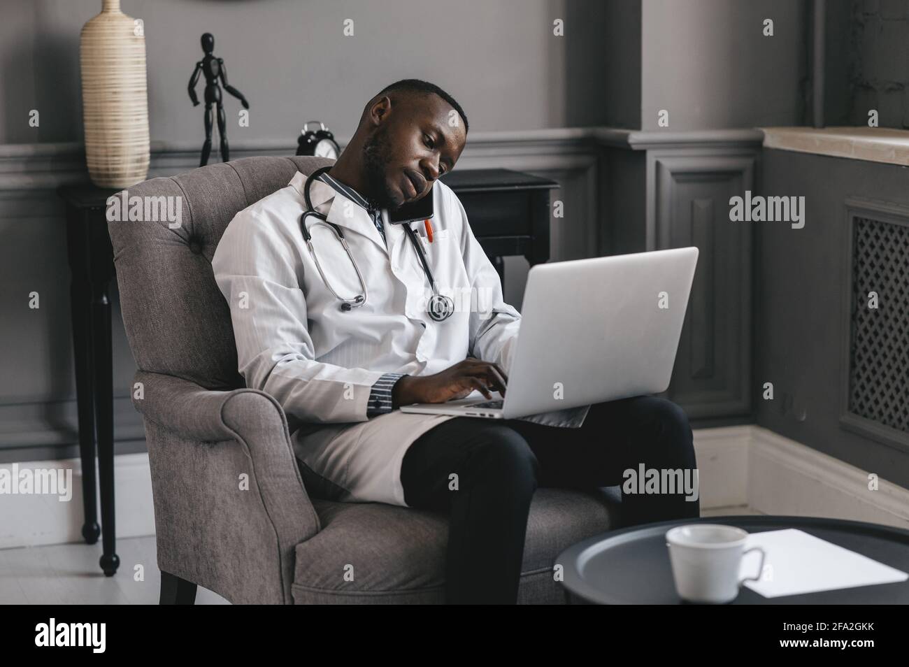 dark-skinned doctor talking on the phone with a laptop Stock Photo - Alamy