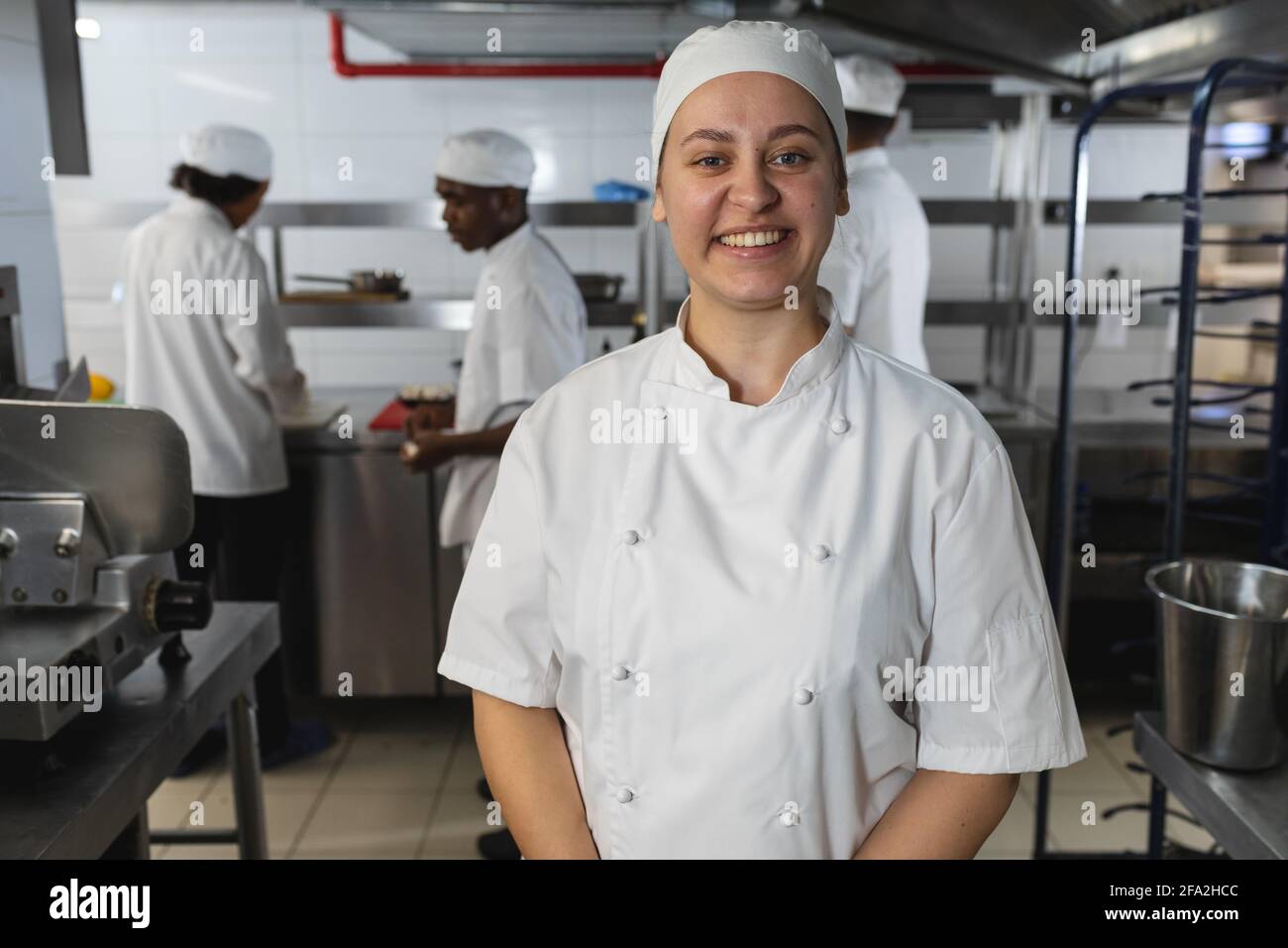 Portrait of caucasian female professional chef with diverse colleagues ...