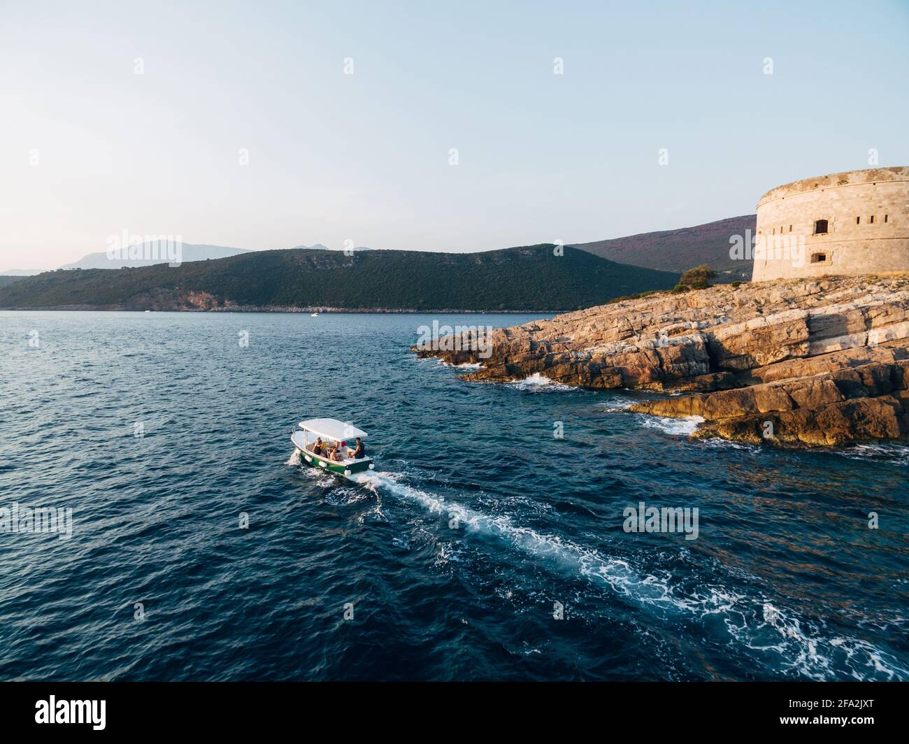 White motor boat with a canopy carries tourists along the coast in the ...