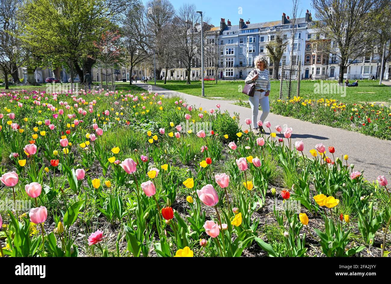 Brighton UK 22nd April 2021 - A woman walks by a carpet of colourful ...