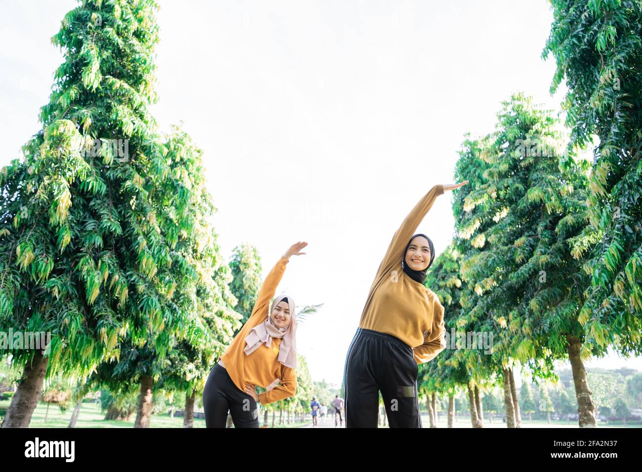 view from below of two girls in veil do arm stretches by raising their ...