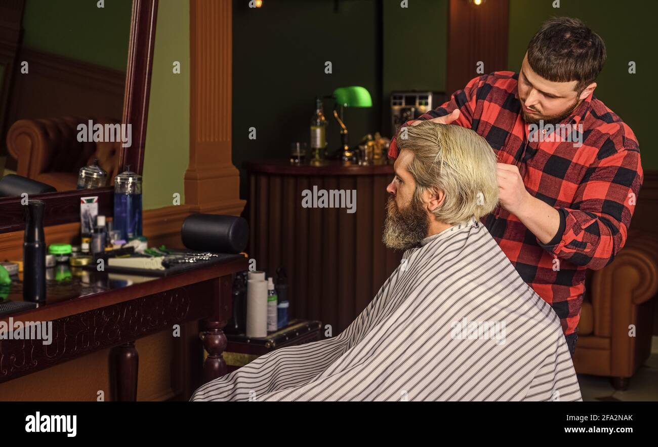 Guy with long dyed blond hair. Professional hairstylist in barbershop ...