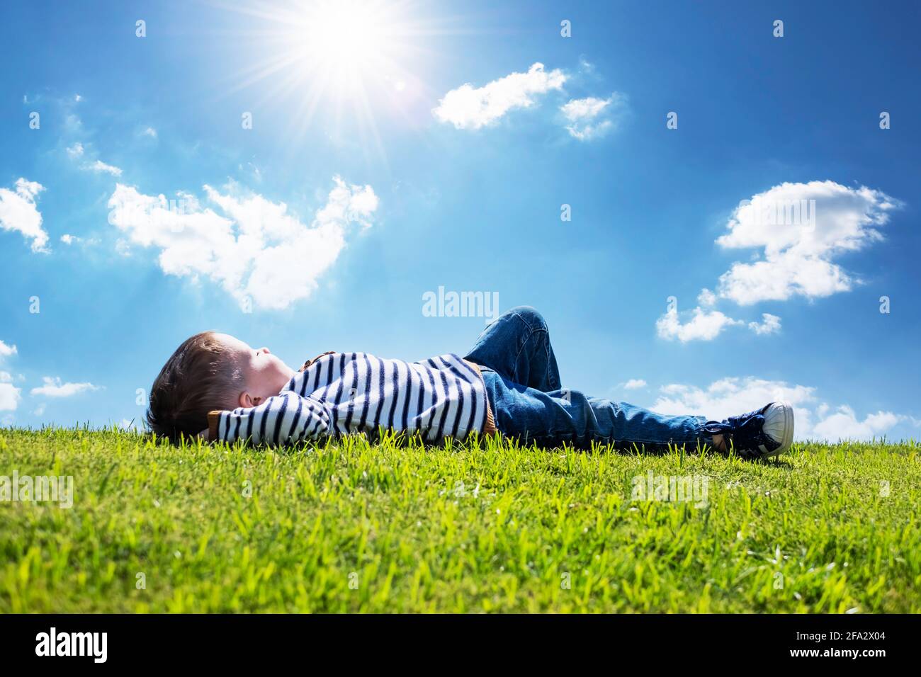 Happy little boy laying on green grass Stock Photo - Alamy