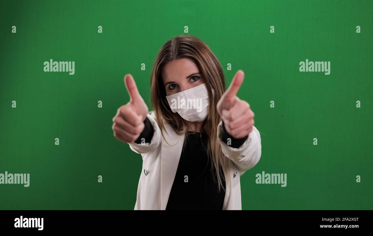Young woman wearing face mask makes thumbs up gesture Stock Photo - Alamy