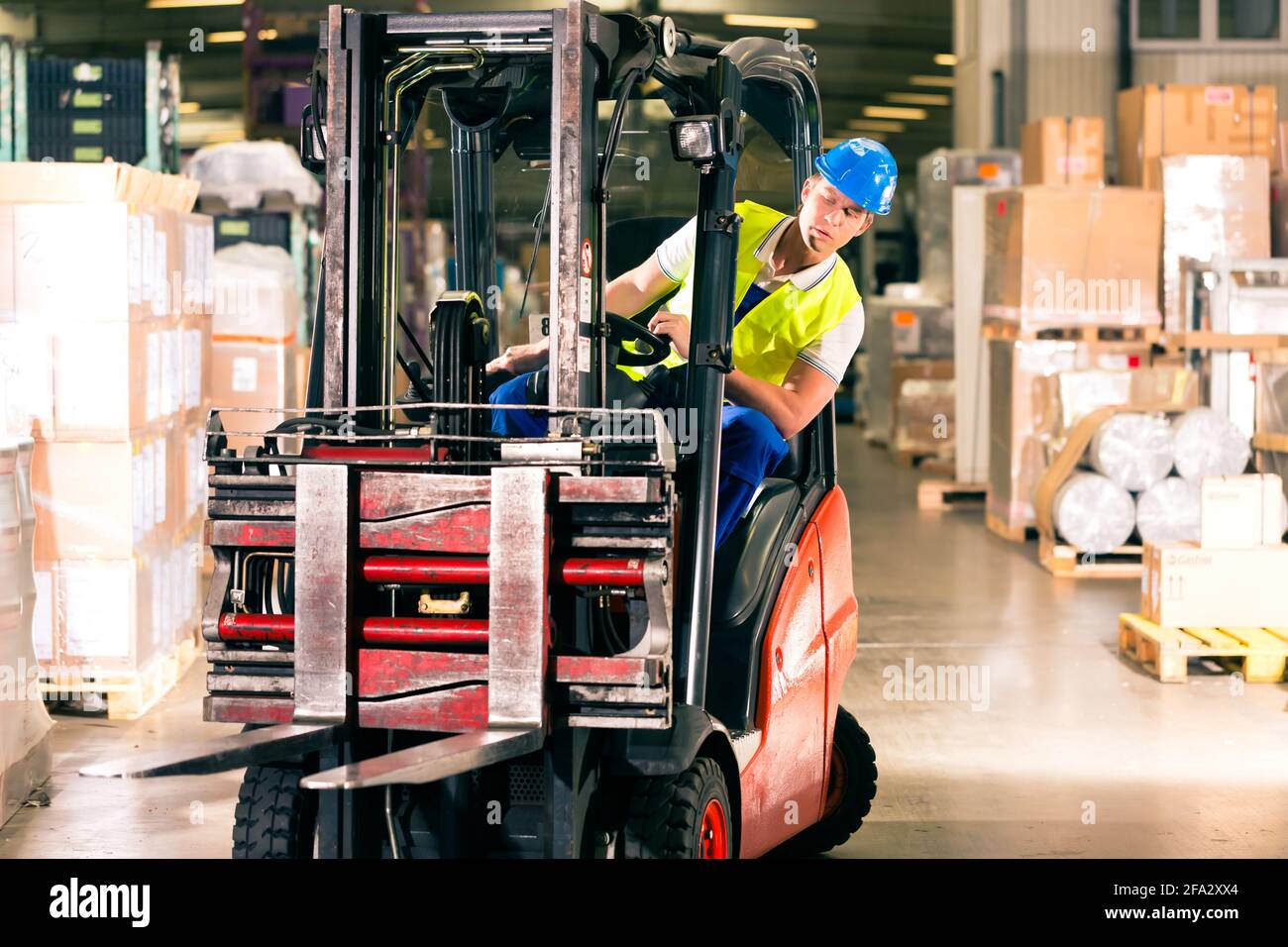 forklift driver in protective vest driving forklift at warehouse of ...
