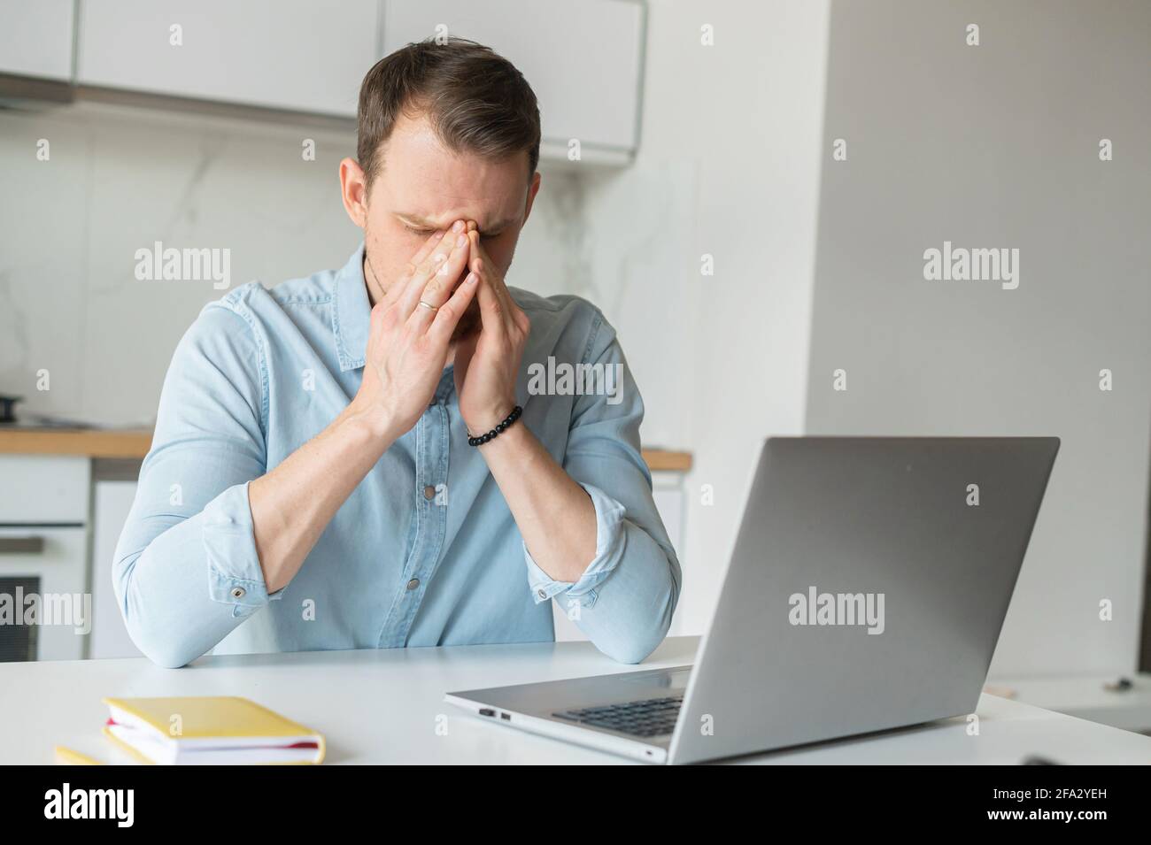 Exhausted young freelancer guy has vision problem after long-time work ...