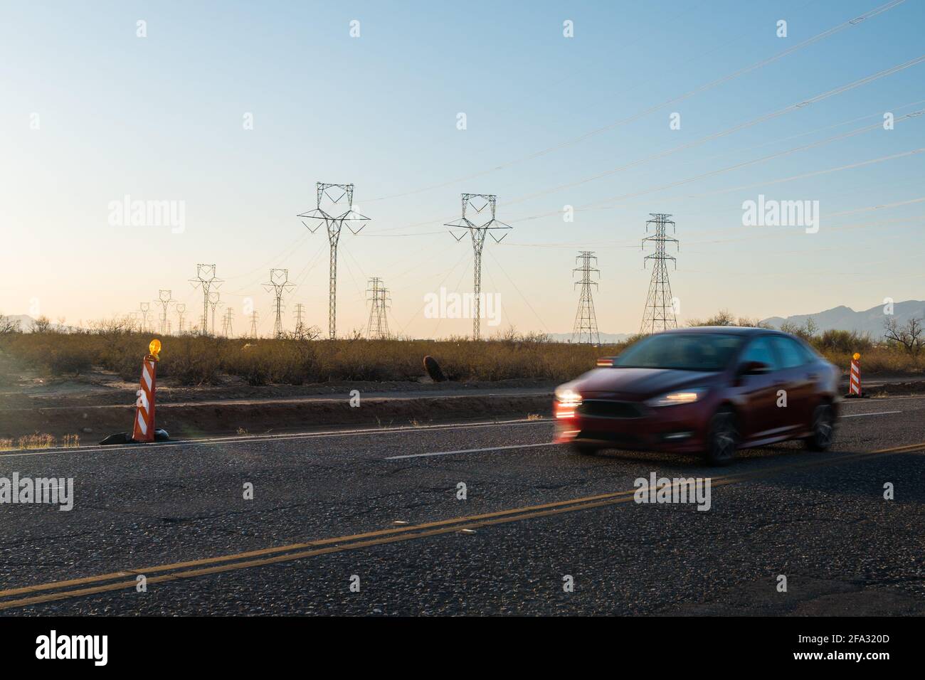Electric pylons at sunset. Cars drive by on street Stock Photo - Alamy