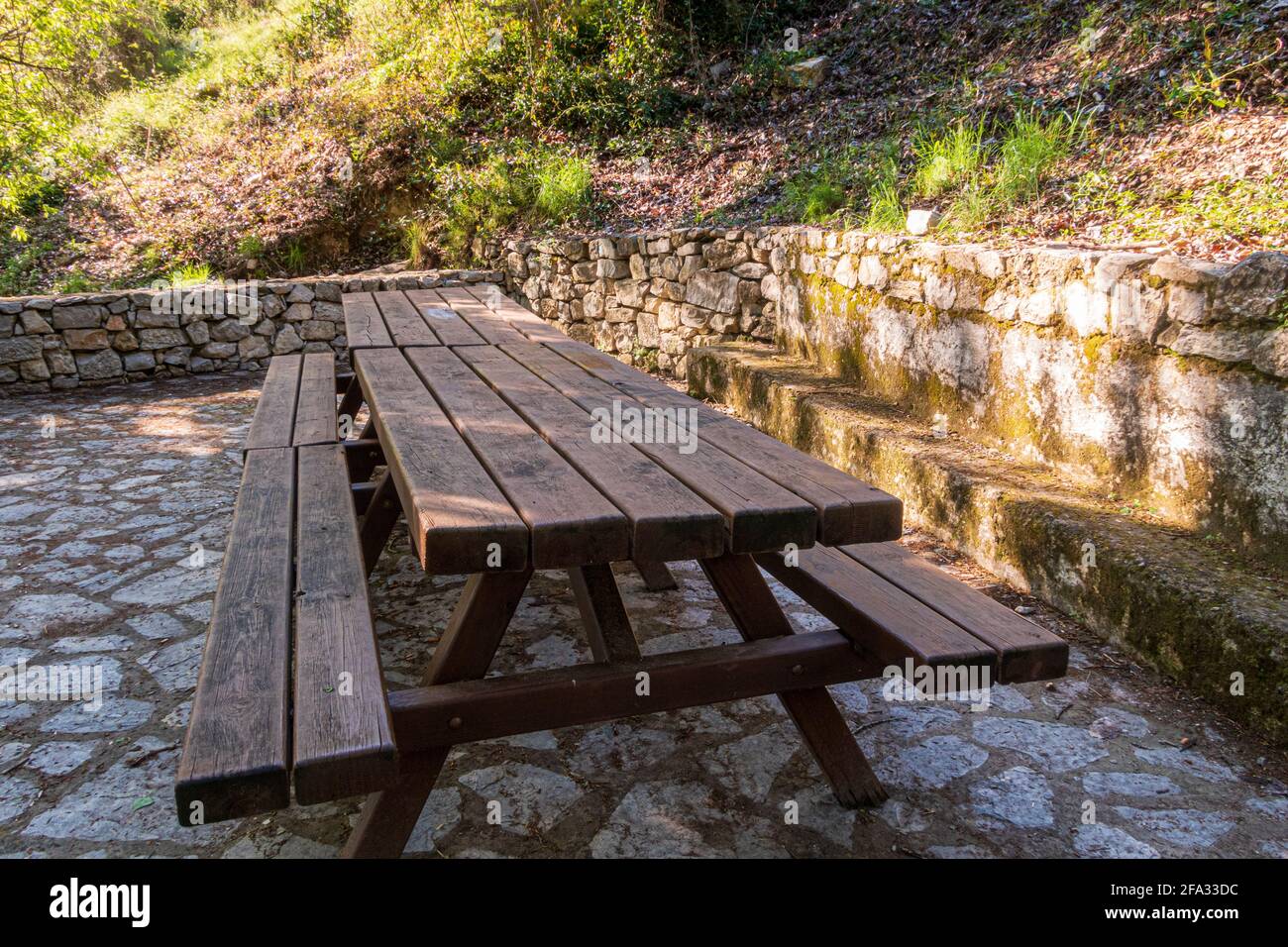 Long wooden table with inbuilt benches on cobbled ground outside ...
