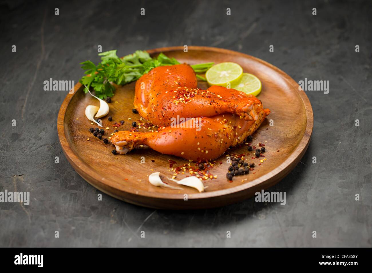 Marinated chicken leg without skin arranged in a wooden base and ...
