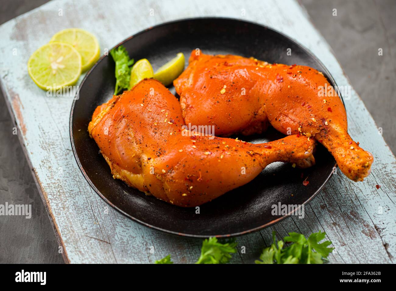Marinated chicken leg without skin arranged in a black plate and ...
