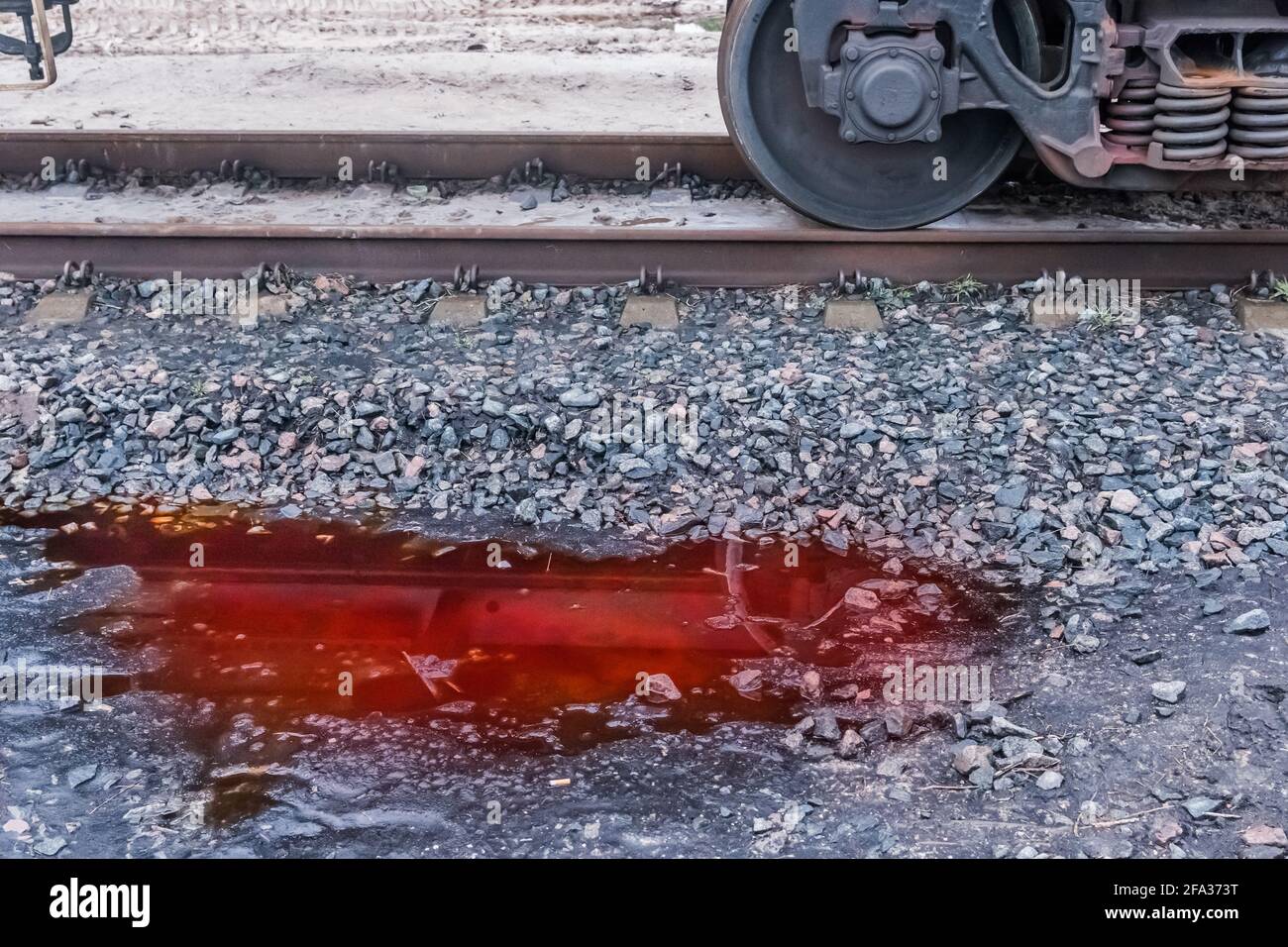 A puddle of red potash fertilizers after rain on crushed stones near ...