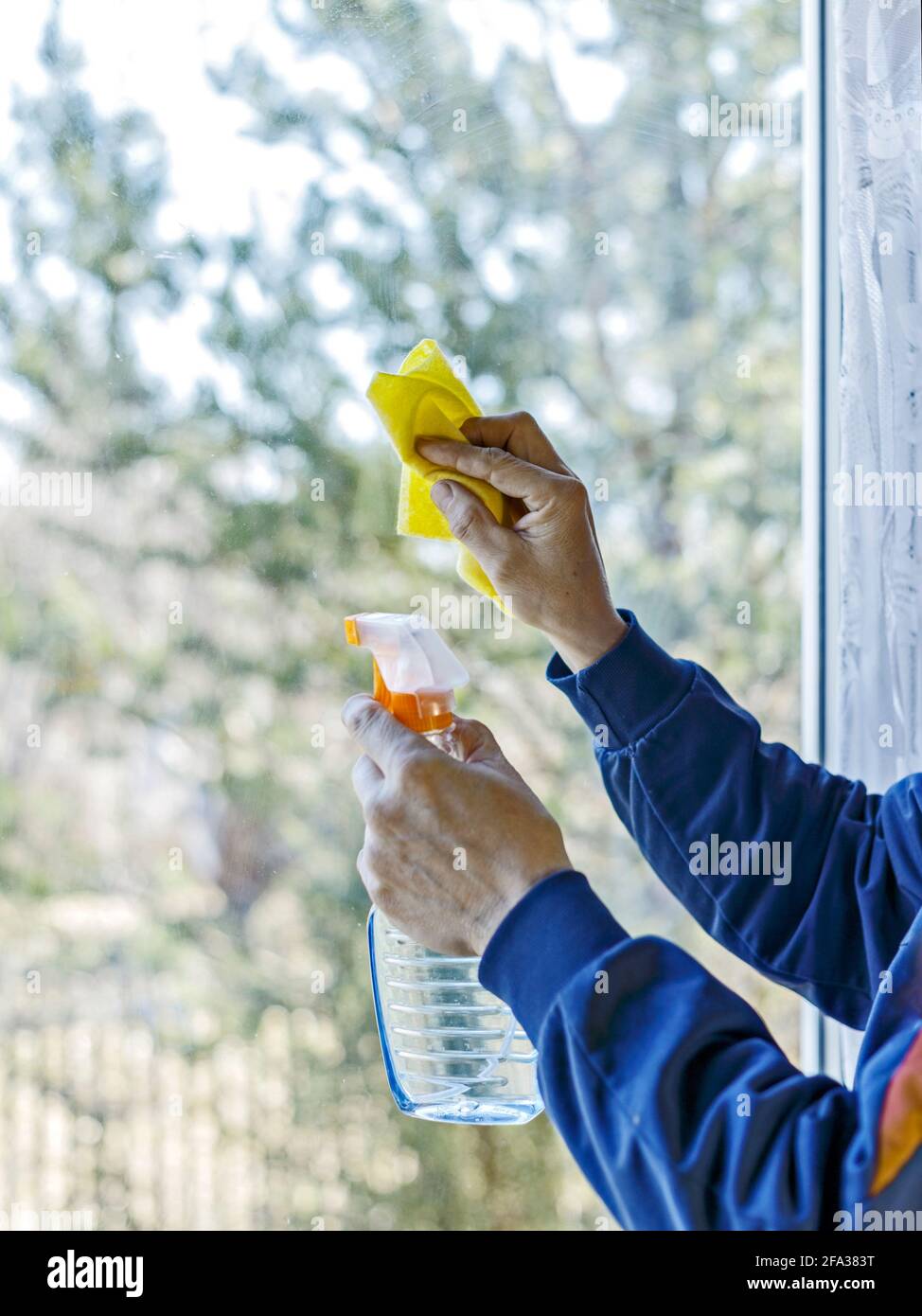 Man wipes glass window using spray Stock Photo - Alamy