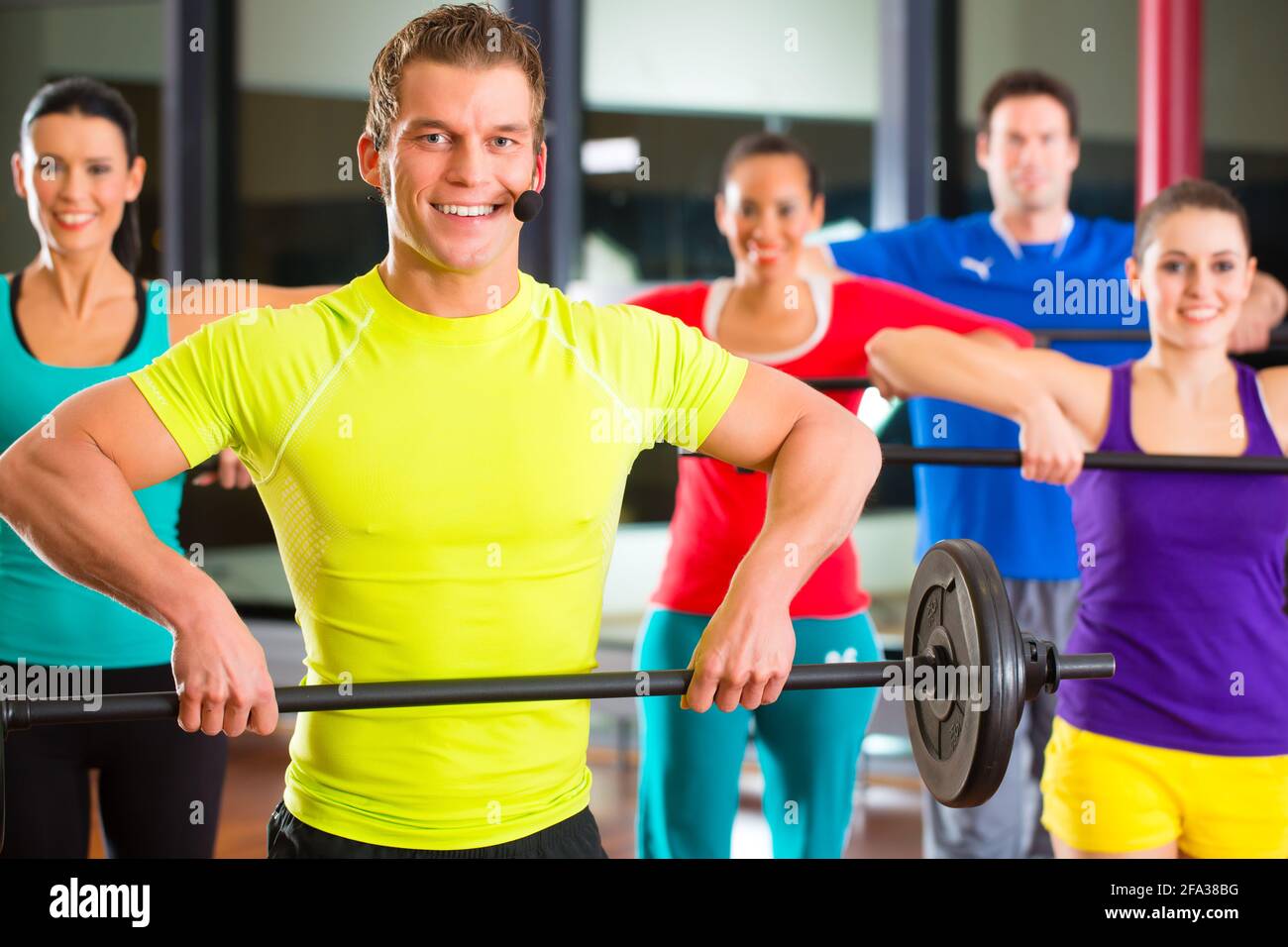 group of young sport people training with barbell at a gym for better ...