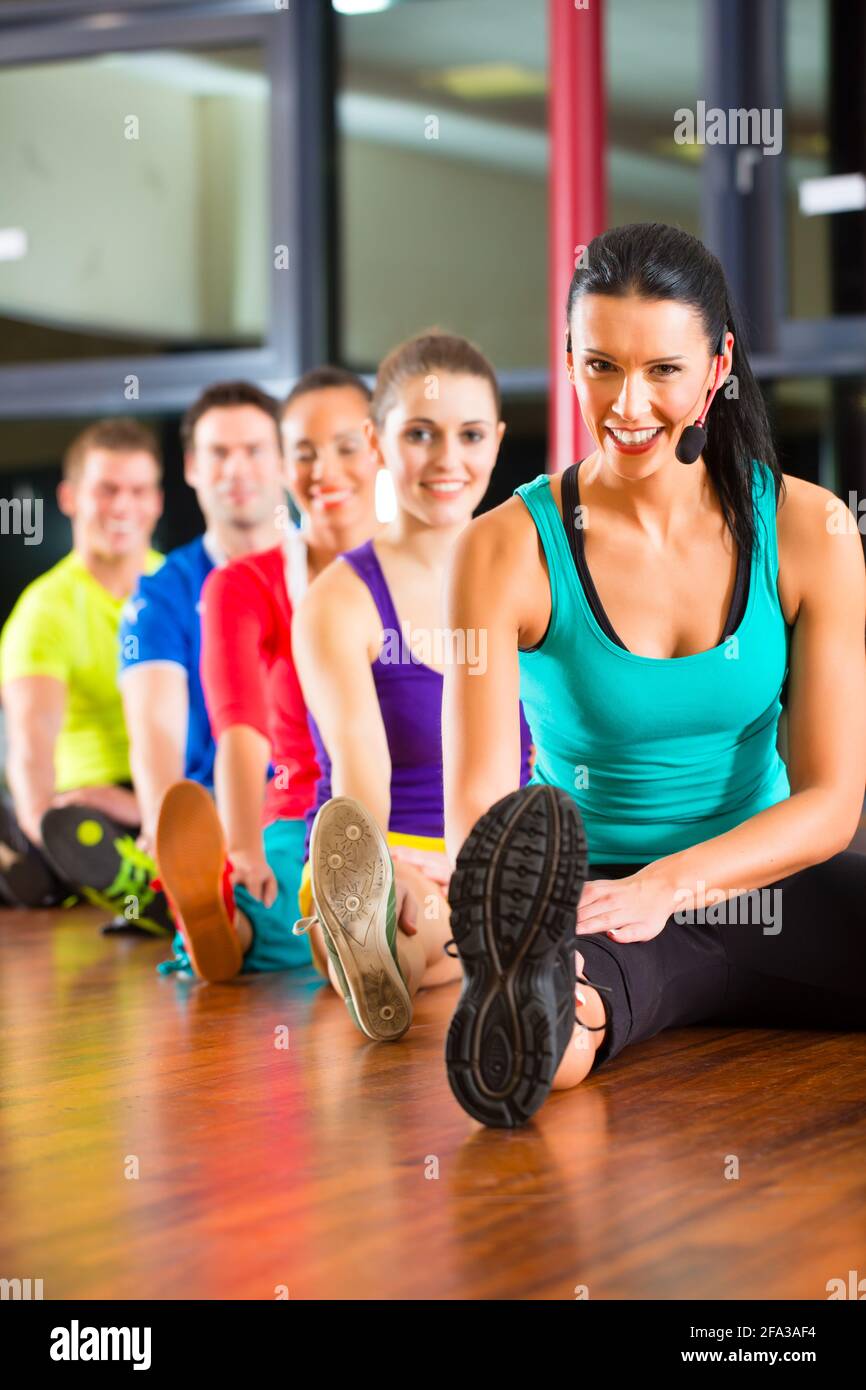 Group of young people stretching in gym for better fitness led by ...