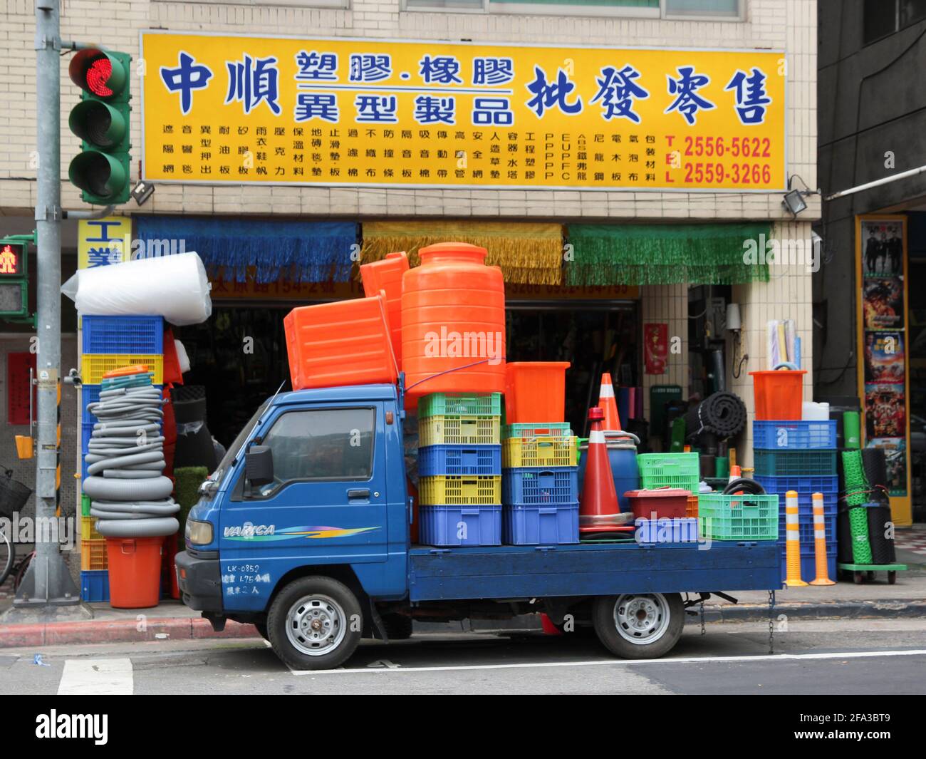 A small, blue pickup, utility truck fully loaded with orange, pink ...