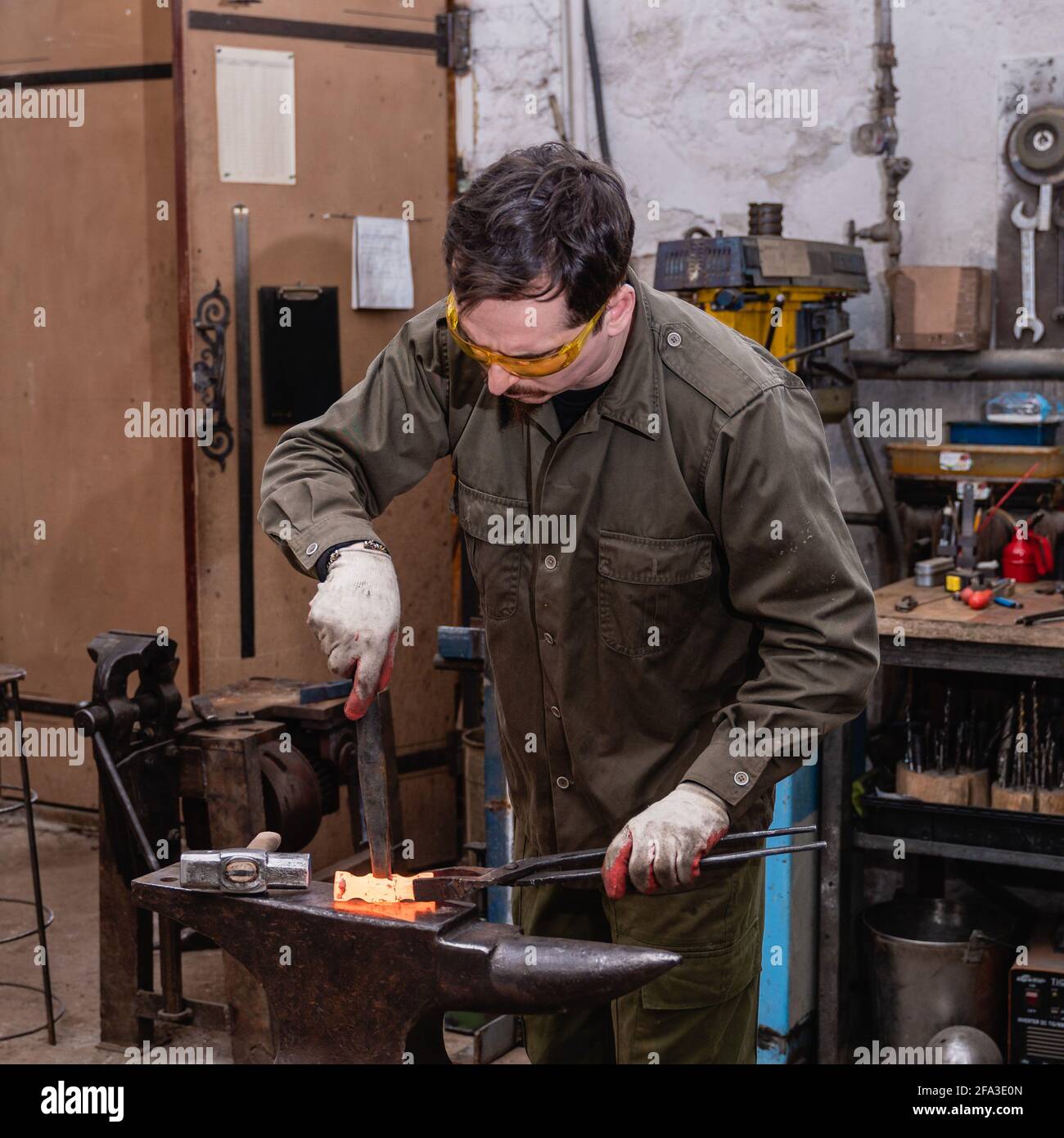 Traditional metalworking process in a forge. A blacksmith forges a red ...
