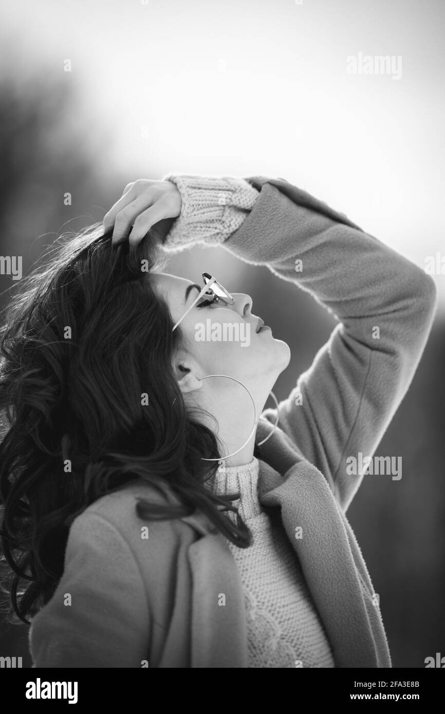 Vertical grayscale shot of a young caucasian female posing outdoors ...