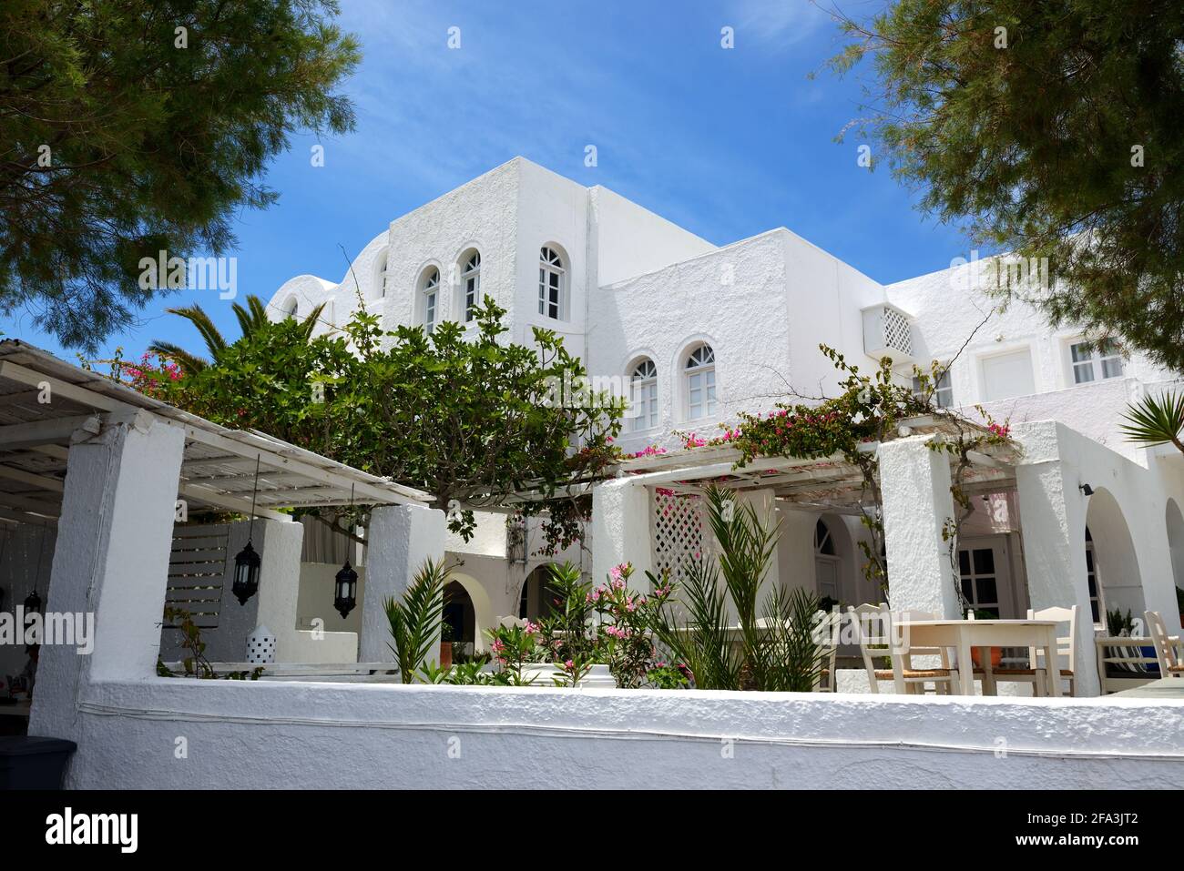 Building of hotel in traditional Greek style with outdoor restaurant ...