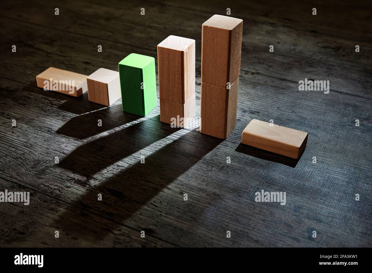 Wooden toy blocks set in graph form growing with green block showing ...