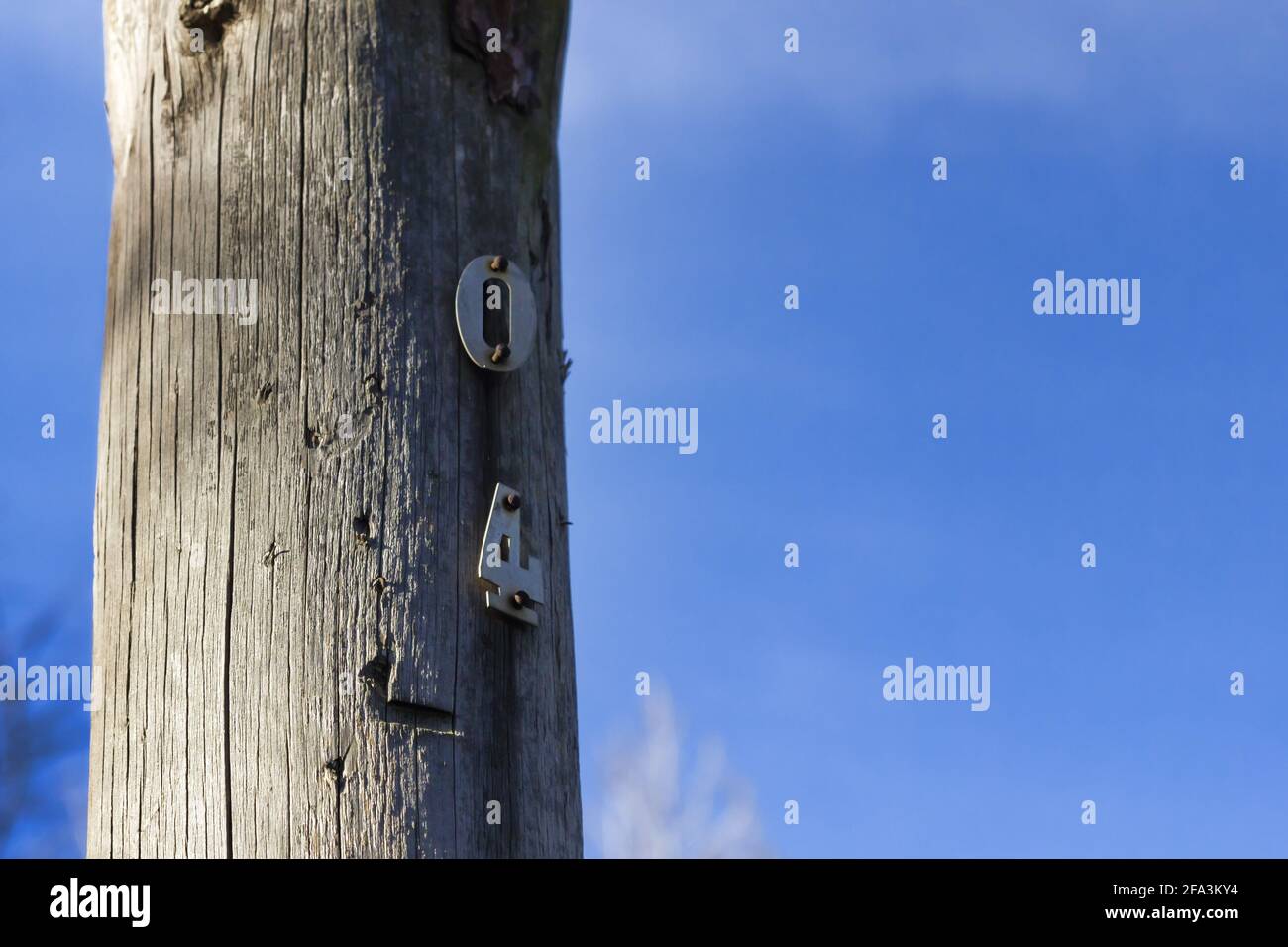 Old wooden telephone pole against blue sky with the numbers 4 and 0 ...