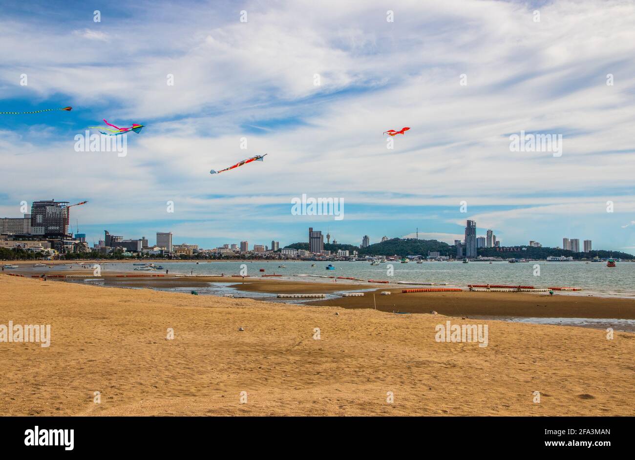 Scenic view of colorful kites flying over Pattaya beach with buildings ...