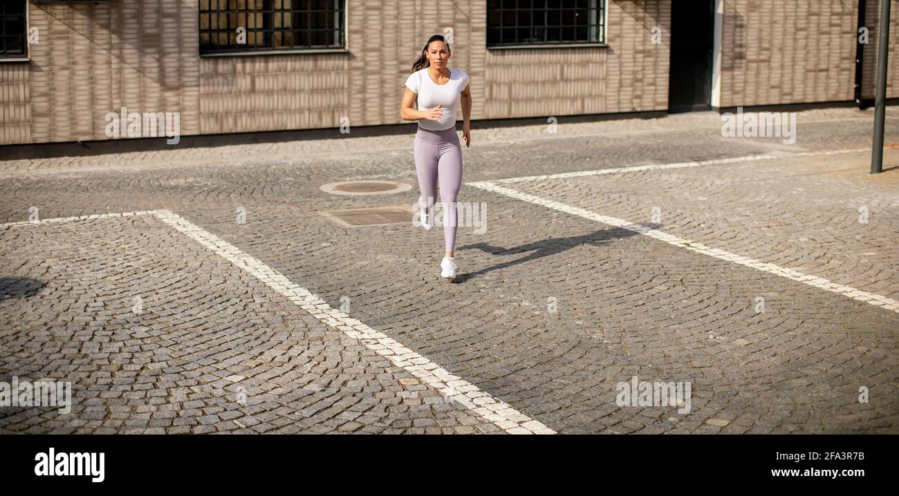 Pretty young woman running on the street Stock Photo - Alamy
