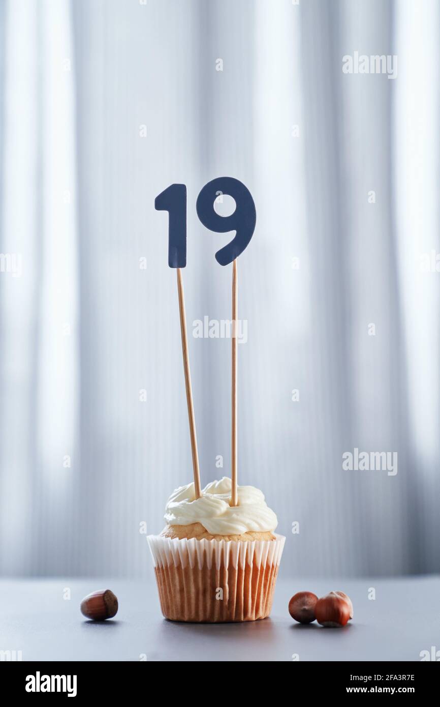 Tasty vanilla cupcake or muffin with number 19 nineteen on white plate ...