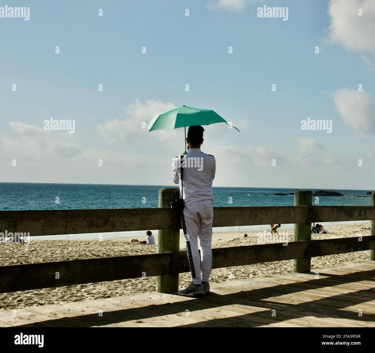 Man at Main Beach boardwalk with green umbrella Stock Photo - Alamy