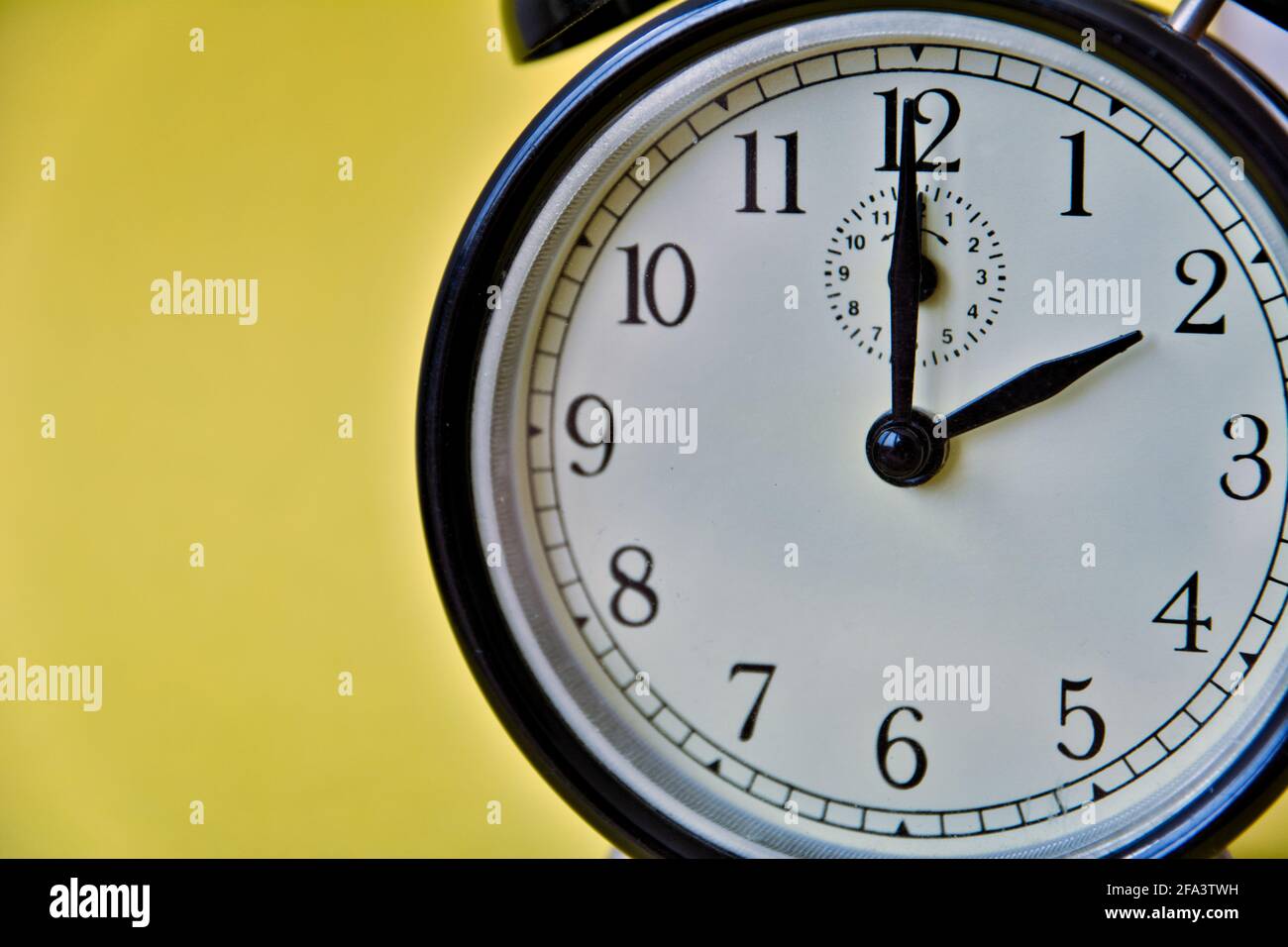 Shot of vintage retro analog clock on yellow background showing 2 o ...