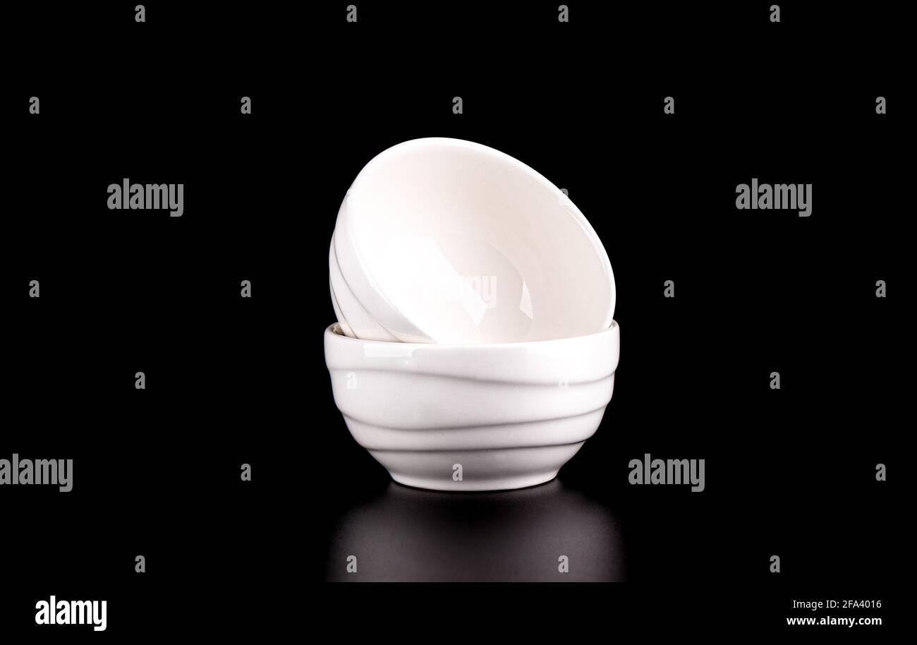 Two porcelain bowls, one inside the other, isolated on a black ...