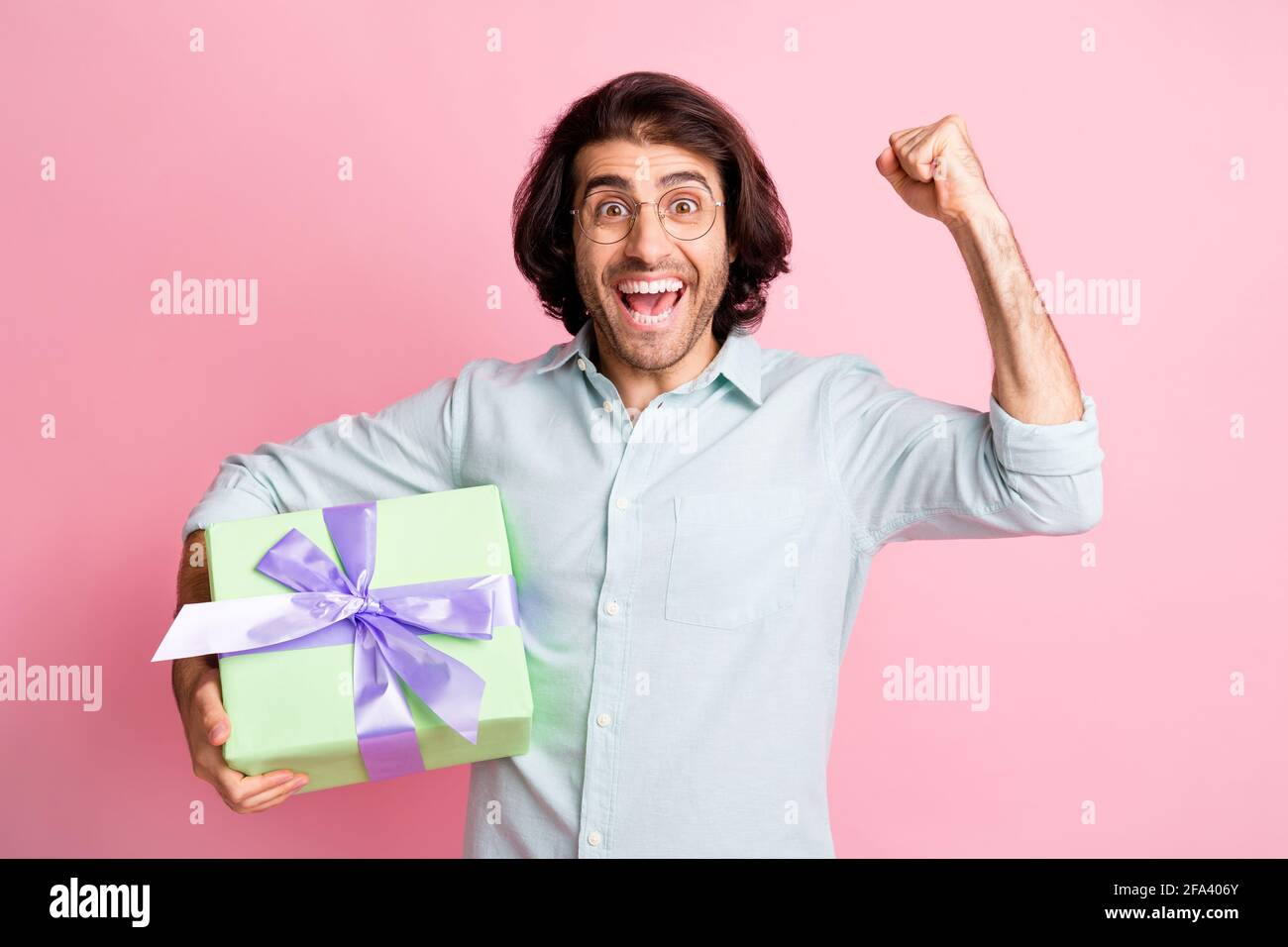 Photo of cheerful funny brown hair guy holding gift fist up wear ...