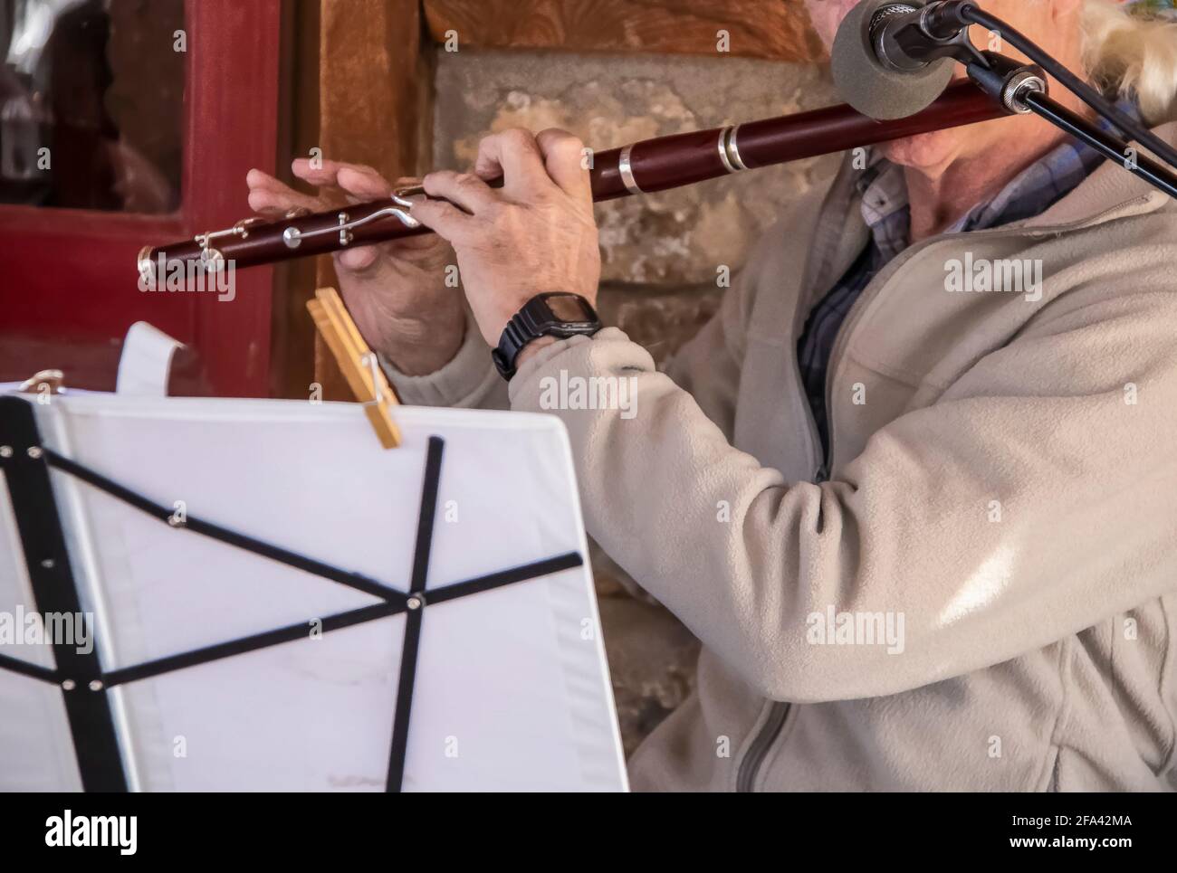 Senior musician -older man plays a flute -closeup with music on stand ...