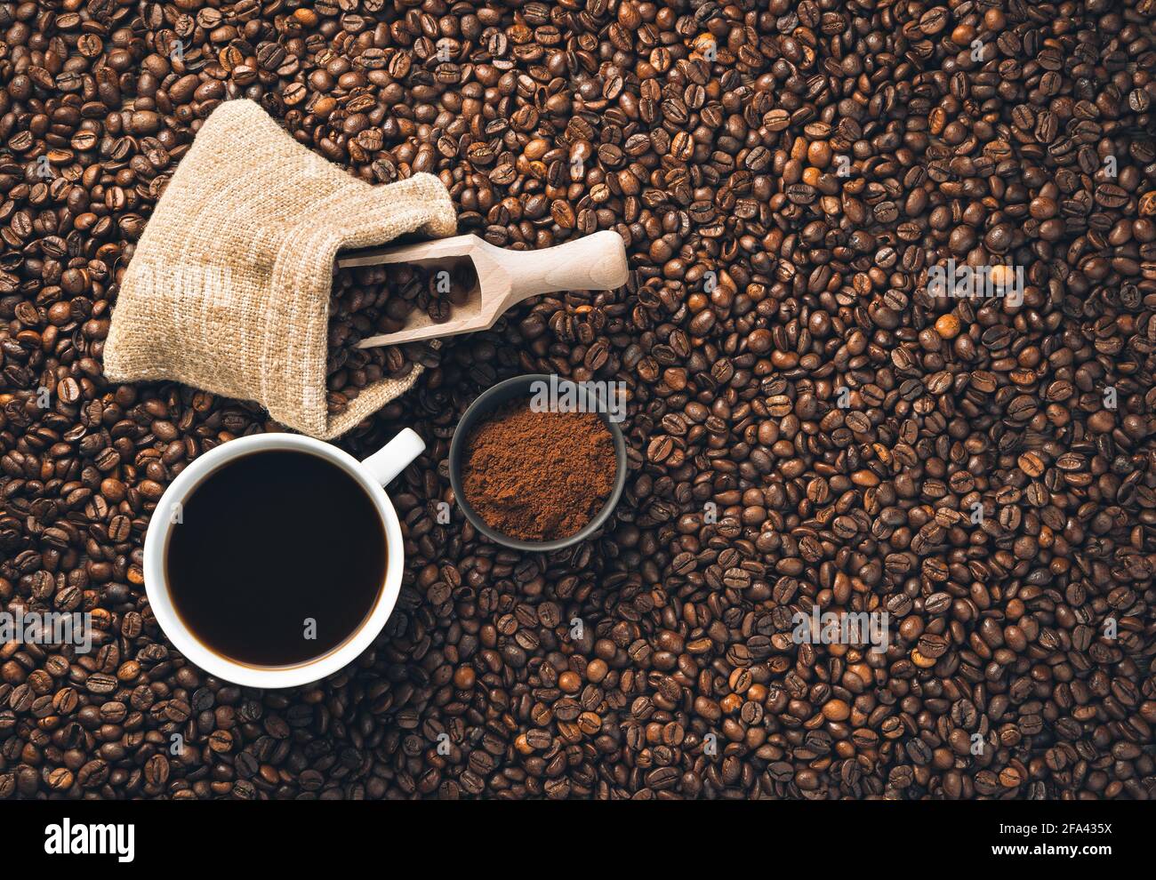 Ground coffee, coffee beans and a cup of coffee on scattered coffee ...