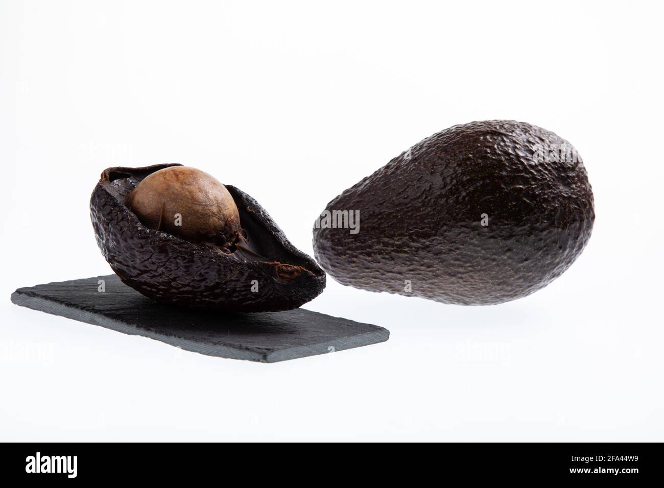 Fresh and ripe avocado next to rotting avocado cut in half with seed ...