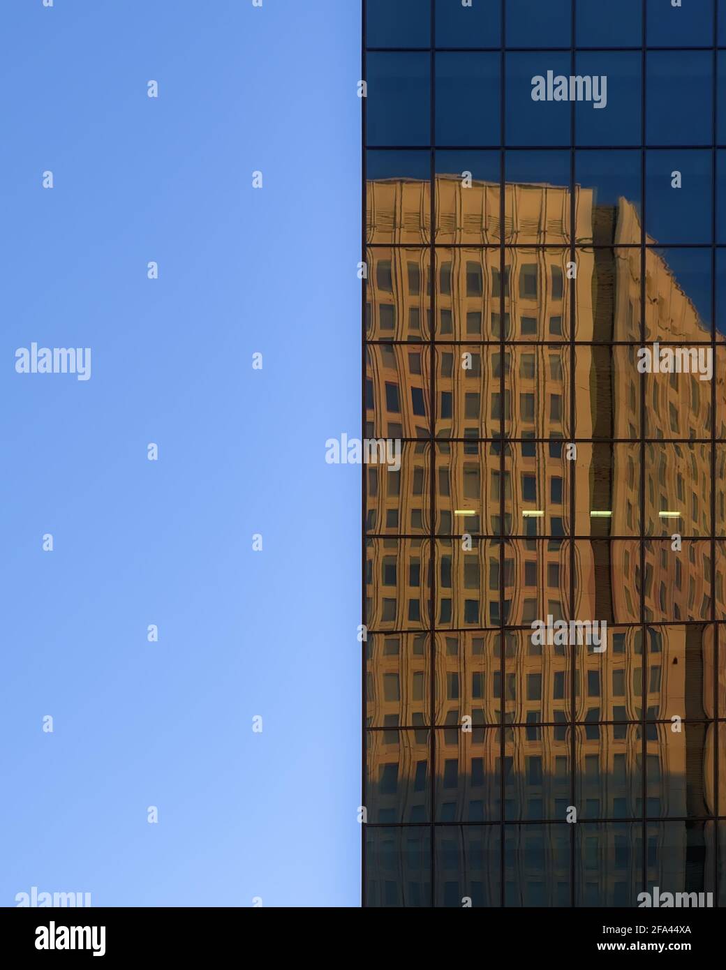 Split perspective of a clear blue sky and the mirrored glass exterior ...