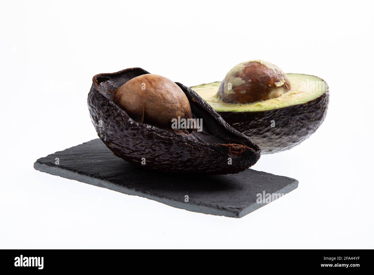 Fresh and ripe avocado next to rotting avocado cut in half with seed ...