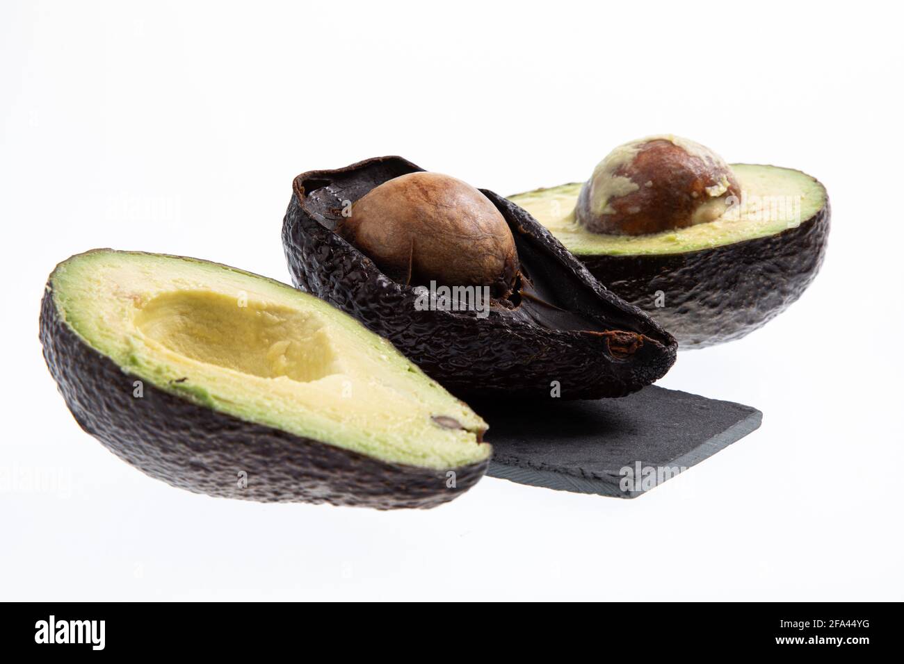 Fresh and ripe avocado next to rotting avocado cut in half with seed ...