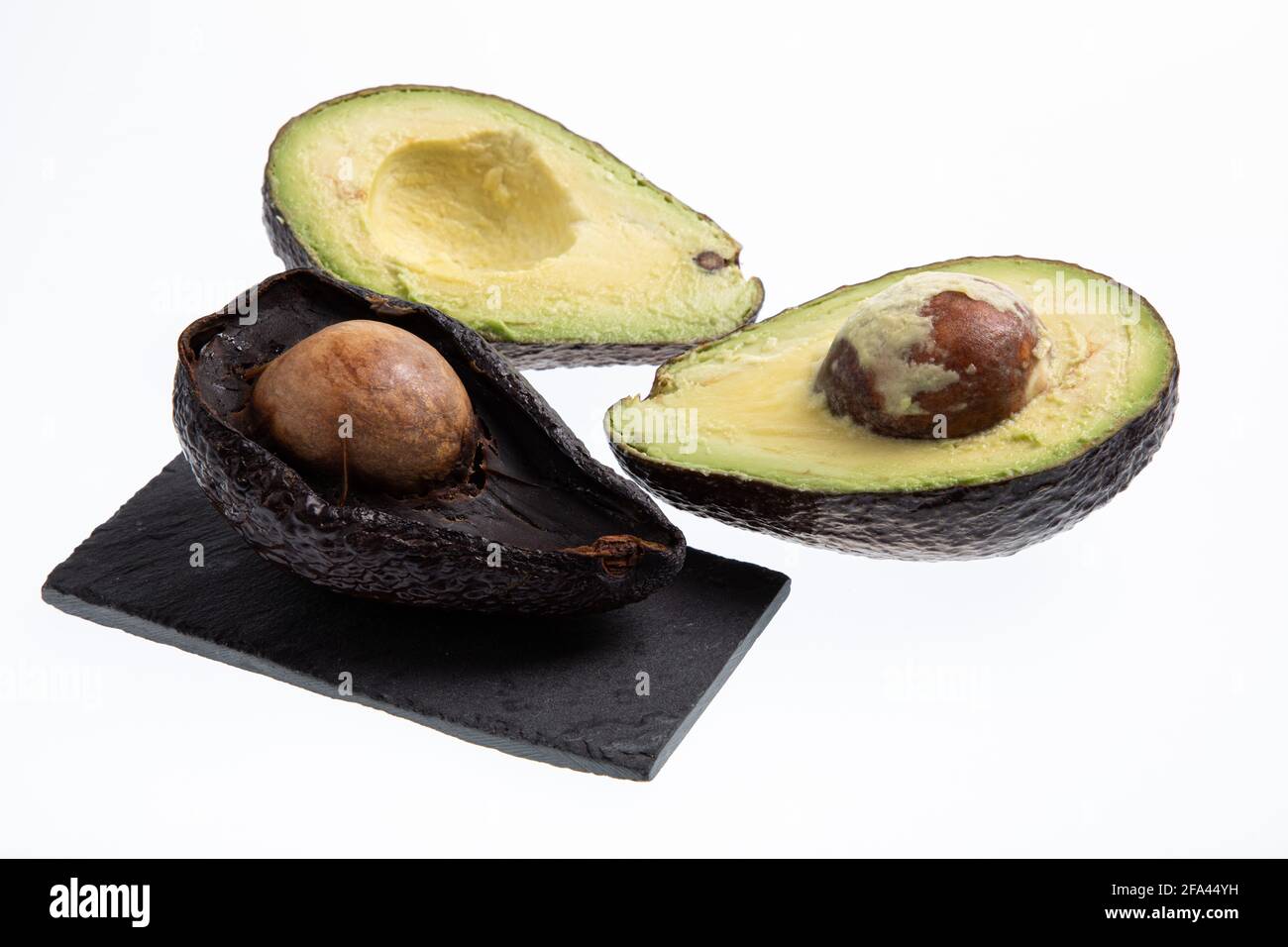 Fresh and ripe avocado next to rotting avocado cut in half with seed ...