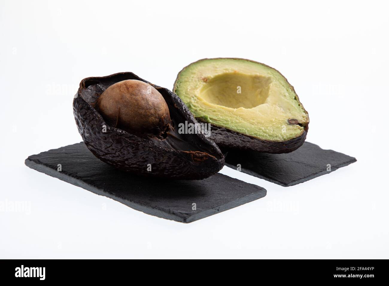 Fresh and ripe avocado next to rotting avocado cut in half with seed ...