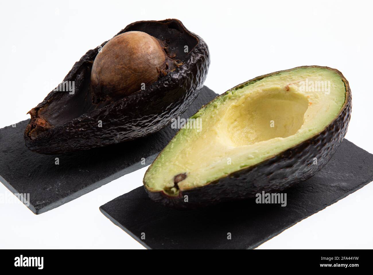 Fresh and ripe avocado next to rotting avocado cut in half with seed ...