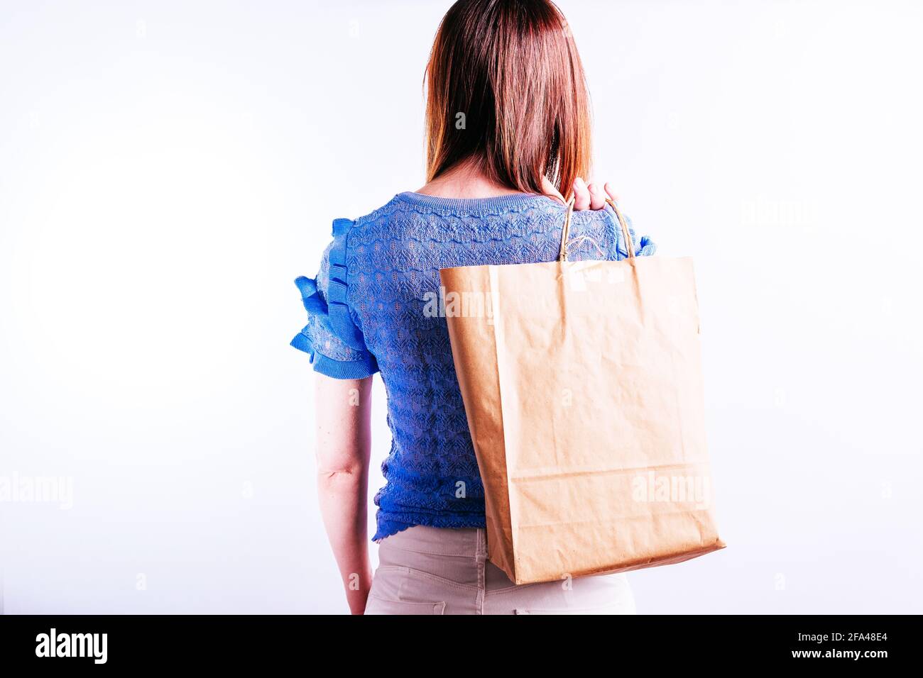 beautiful young woman from behind with a paper bag behind her back ...