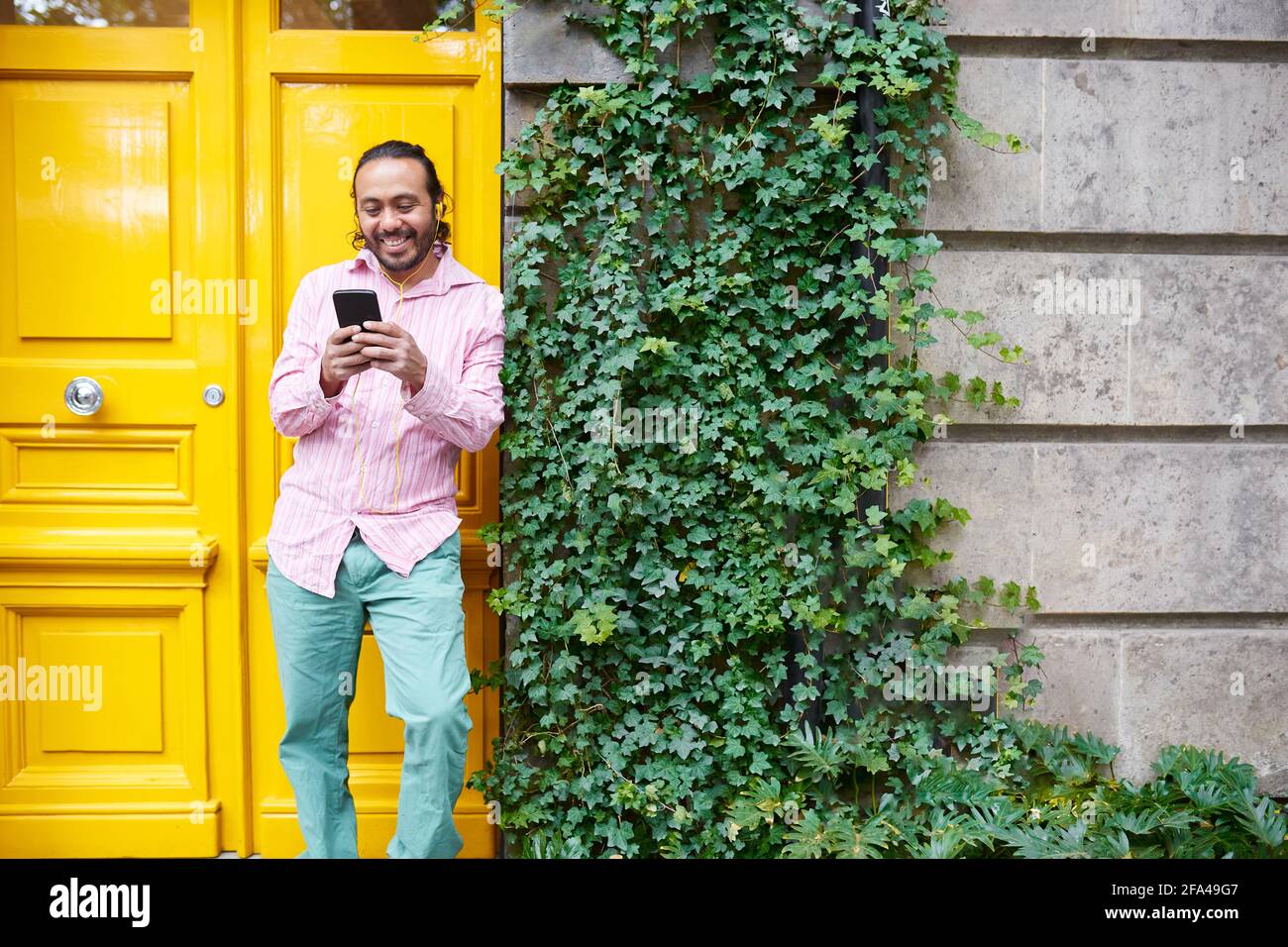 happy young man listening music using his smarthphone on the street ...