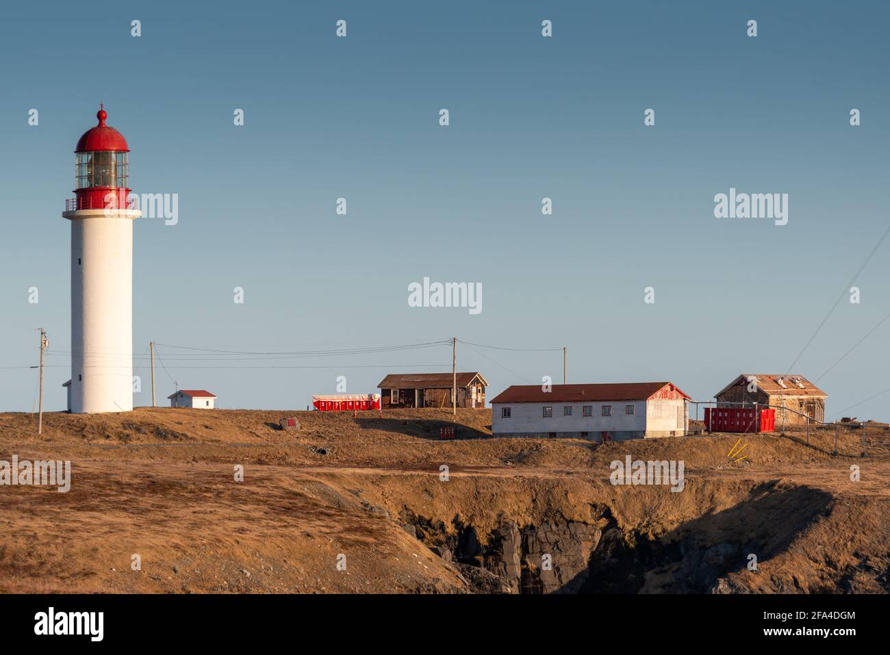 A white and red cylinder shaped concrete lighthouse with a large green ...