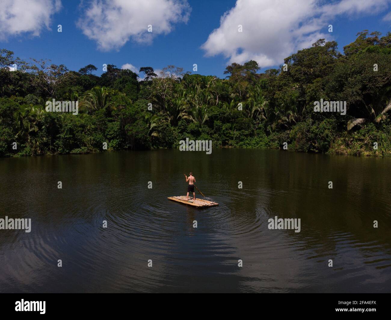Young man standing on wooden raft float on tropical exotic Amazon ...
