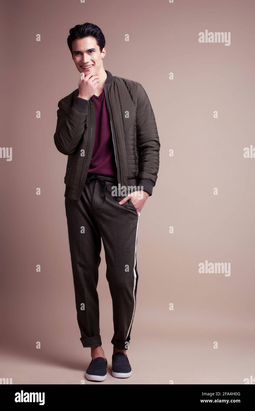 young pretty asian man posing in fashion style on light brown ...